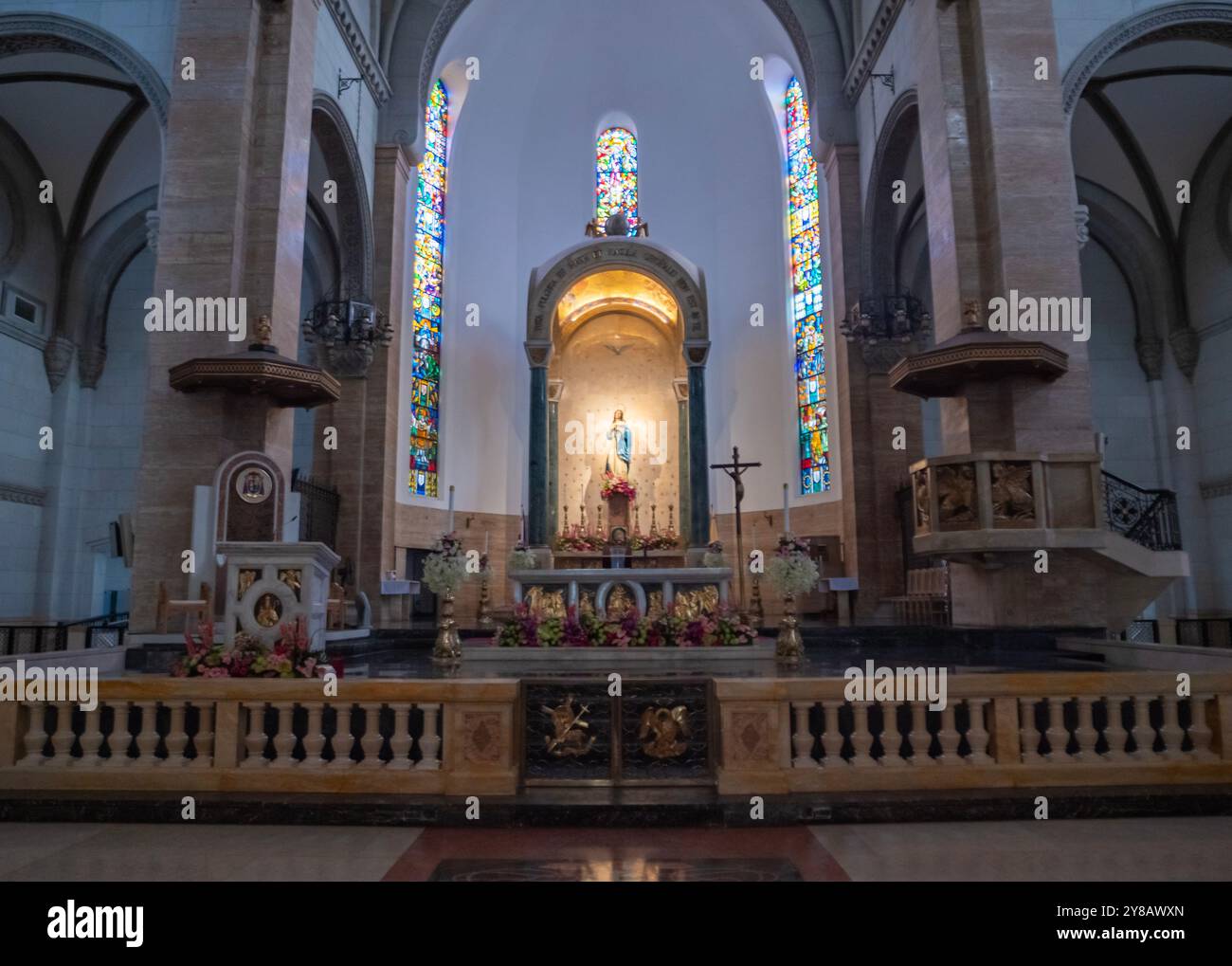 The interior of a church showcases stained glass windows casting ...