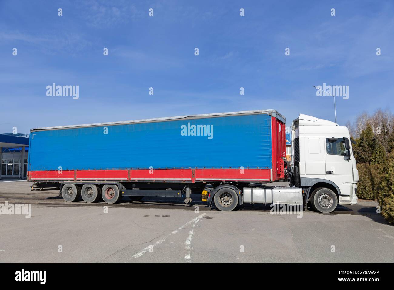 white cabin, blue trailer. A long ten-wheeled truck parked on a sunny ...