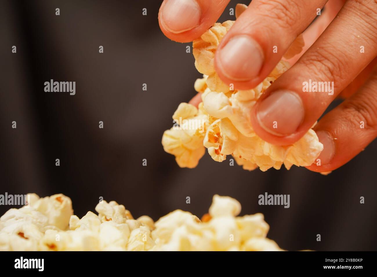 Grabbing popcorn in hand. Delicious snack to eat in the cinema. Salted ...