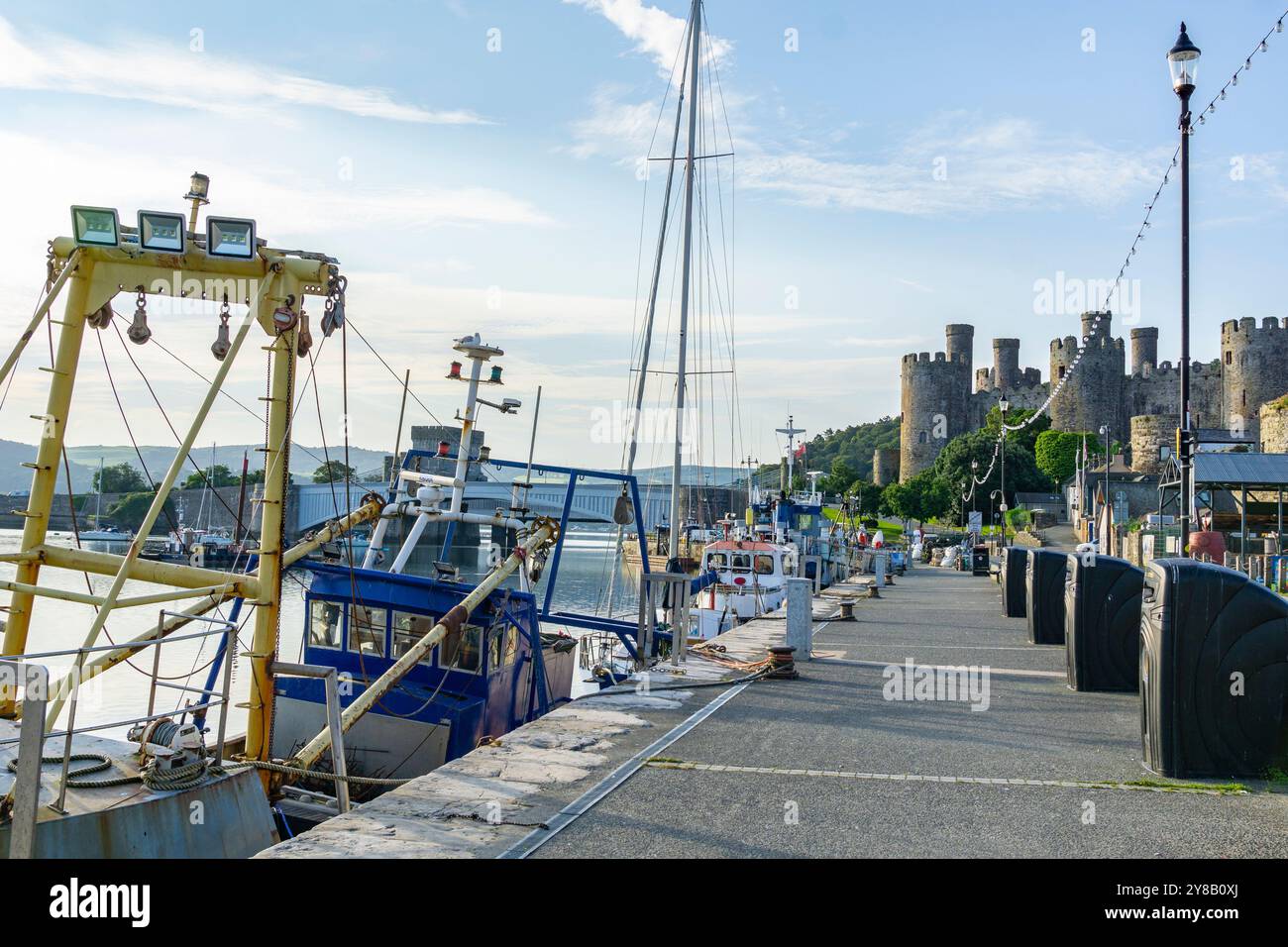 Conwy Castle at end of the Quay with old fishing boats alongside pier ...