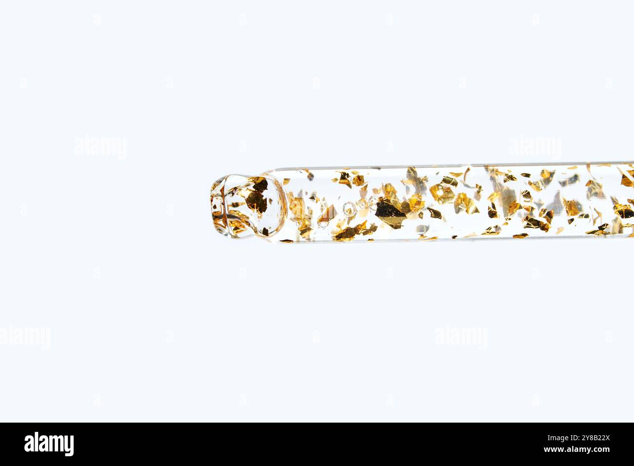 Transparent test tube with gold flakes on white background, modern ...