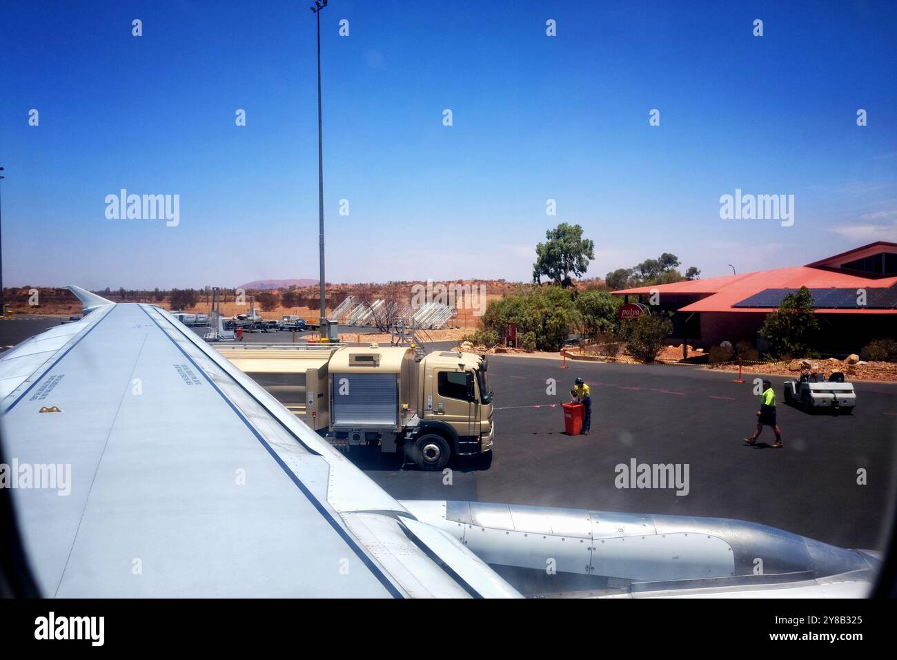 View over aircraft wing of refueling truck and Uluru from Ayers Rock ...