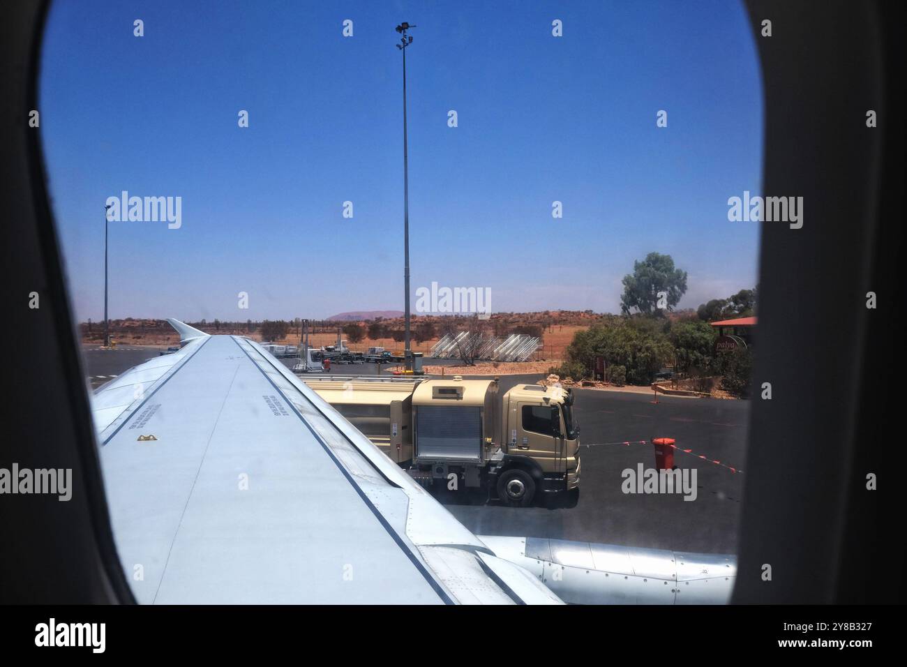 View over aircraft wing of refueling truck on the apron and Uluru from ...