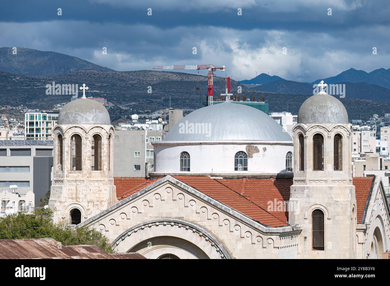 Holy Trinity church with a red tile roof and white stucco walls stands in the middle of Limassol ...