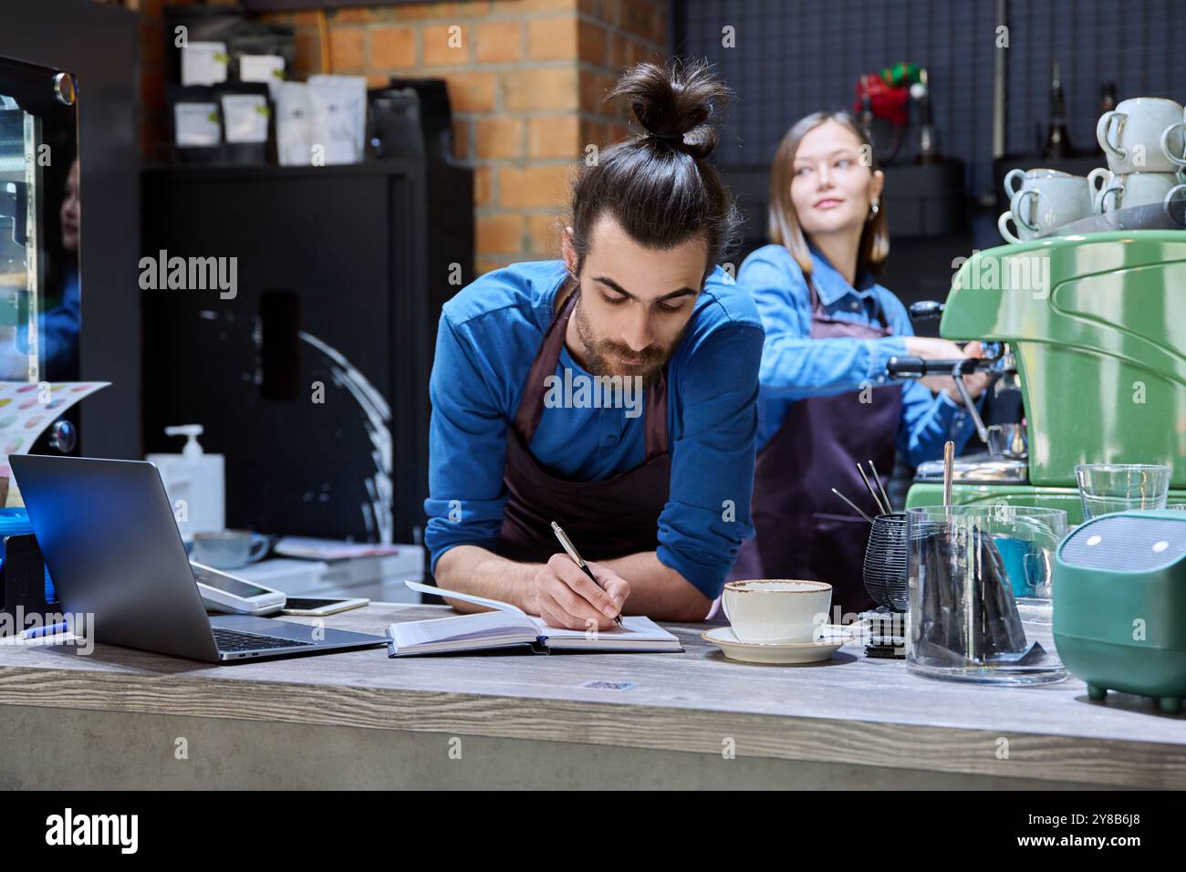 Two cafe workers working together behind counter, at coffee shop Stock ...