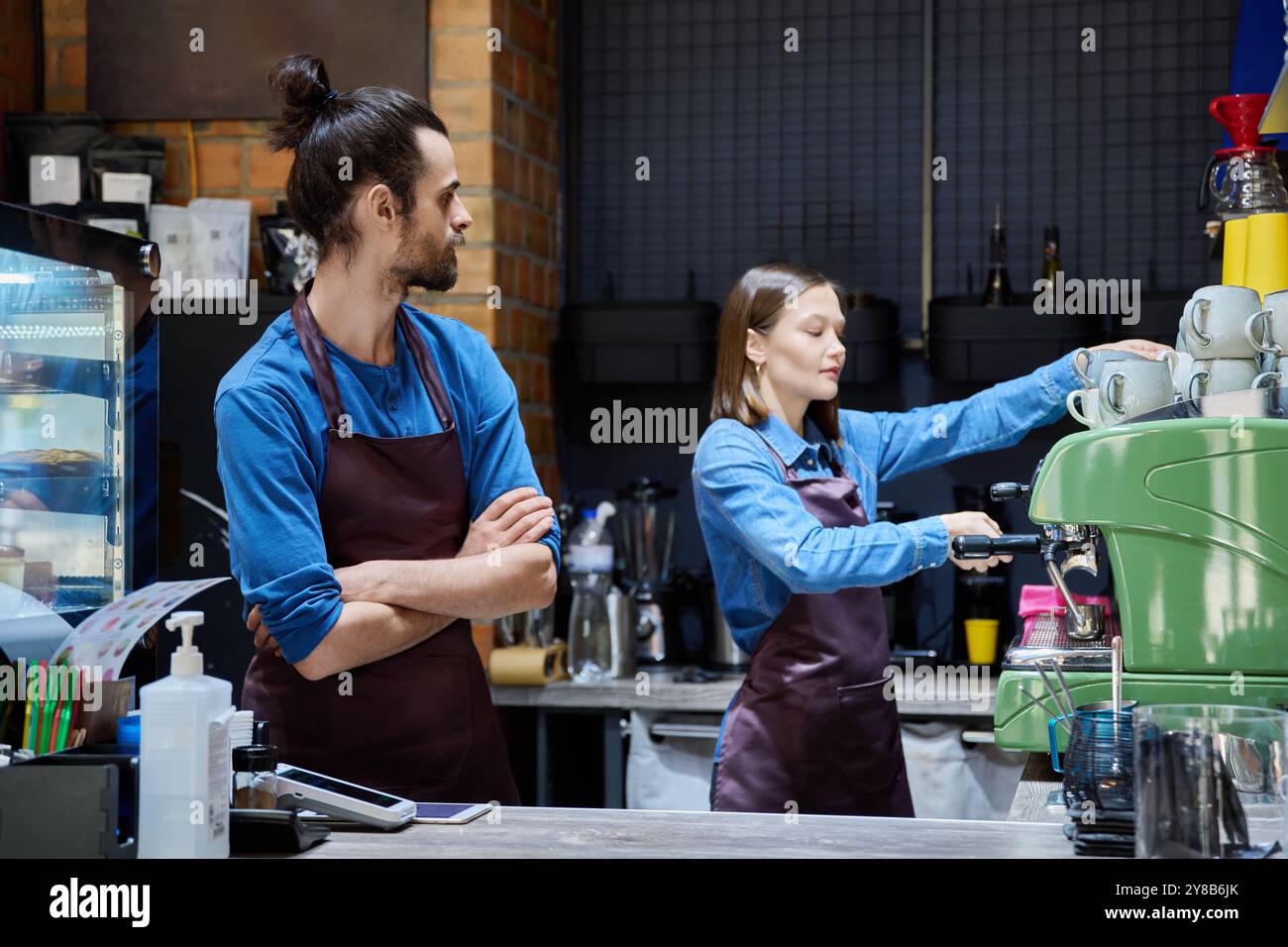 Two cafe workers working together behind counter, at coffee shop Stock ...