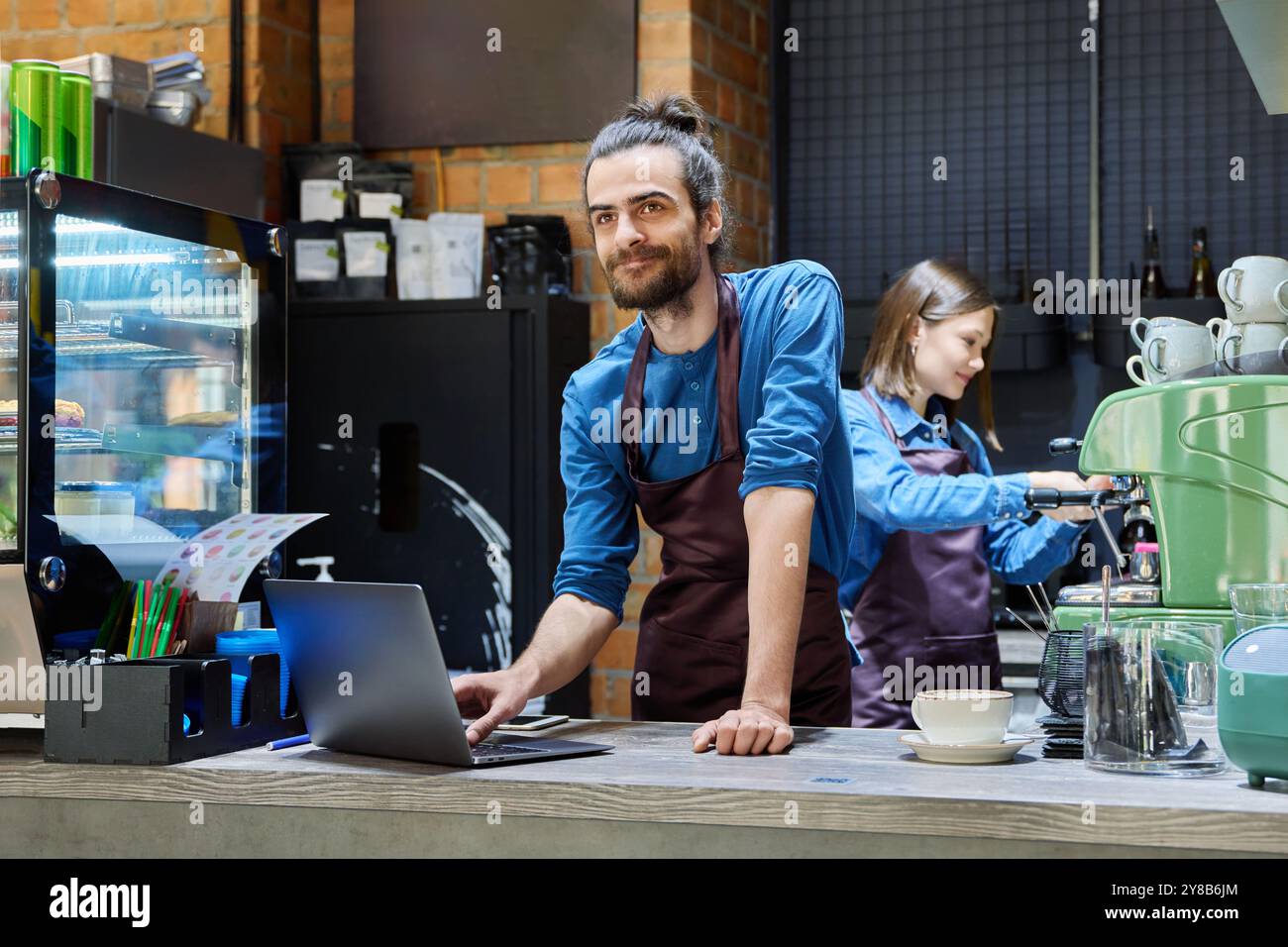 Two cafe workers working together behind counter, at coffee shop Stock ...