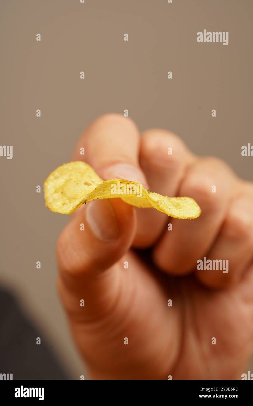 Hand holding potato chip closeup. Calories. Obesity. American food ...