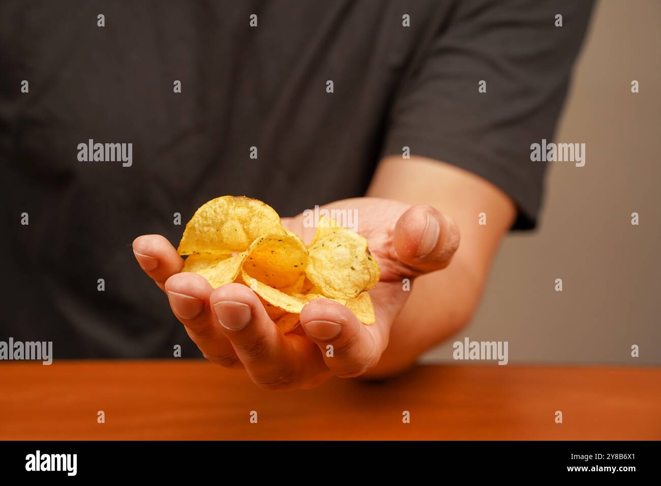 Man eating potato chips. A view of a hand holding a stack of ridged ...