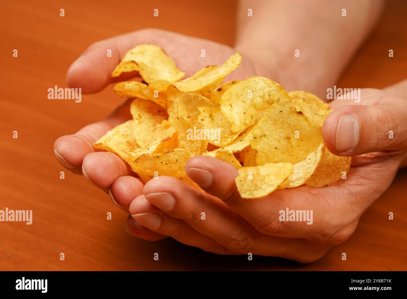 Man eating potato chips. Hands holds potato chips. A view of a hand ...