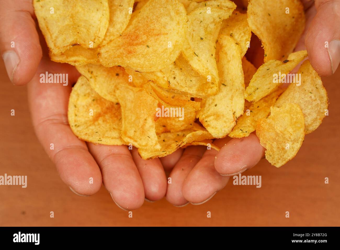 Hands hold potato chips. A view of a hand holding a stack of ridged ...