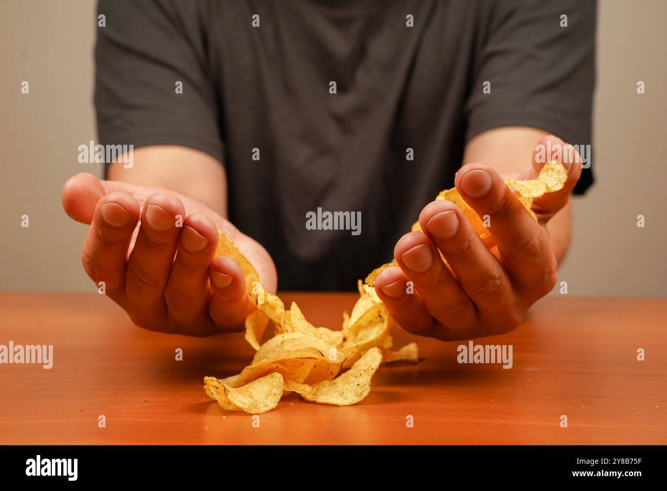 Man eating potato chips. A view of a hand holding a stack of ridged ...