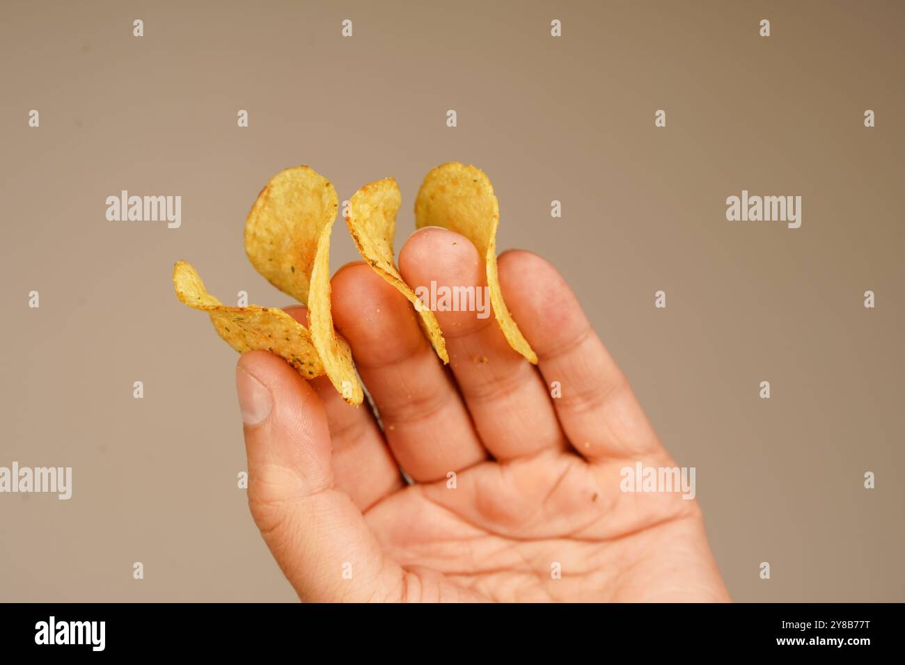 Man eating potato chips. Hand holds potato chips. A view of a hand ...
