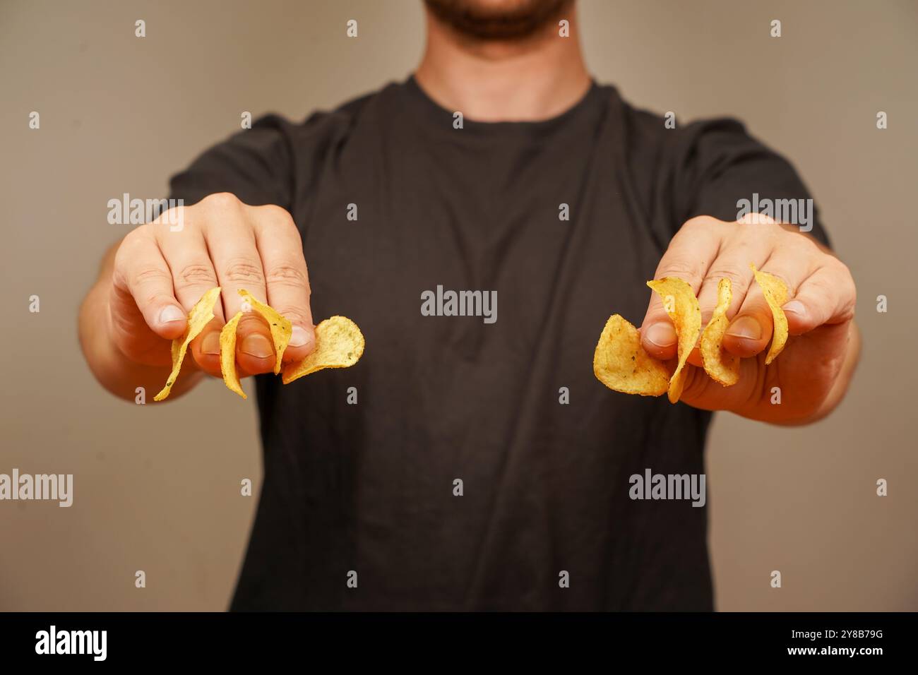 Hands hold potato chips. A view of a hand holding a stack of ridged ...