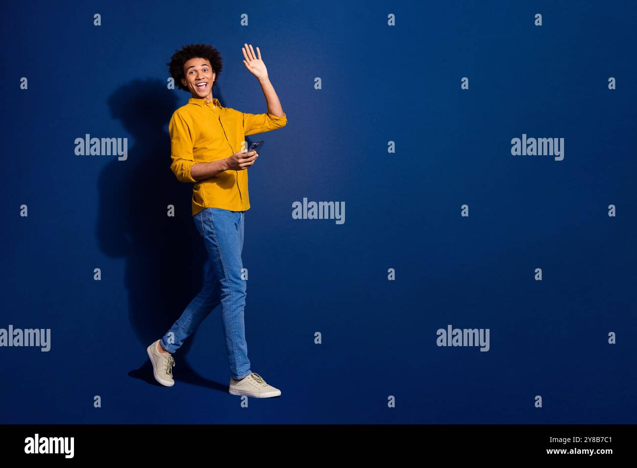 Full size photo of nice young man wave hi walk phone empty space ...