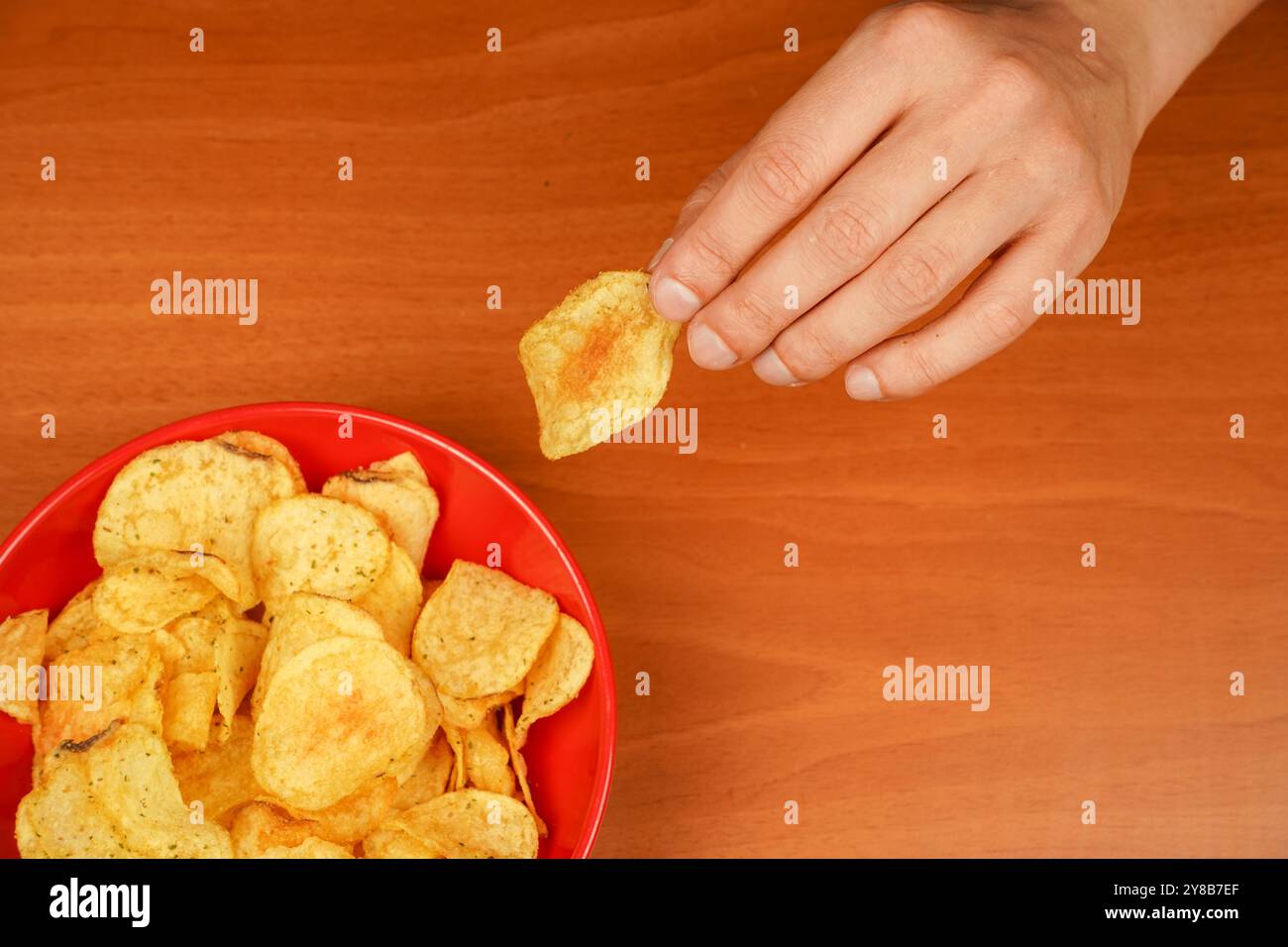 A view of a hand taking potato chips out of bowl. Fast food. Junk food ...