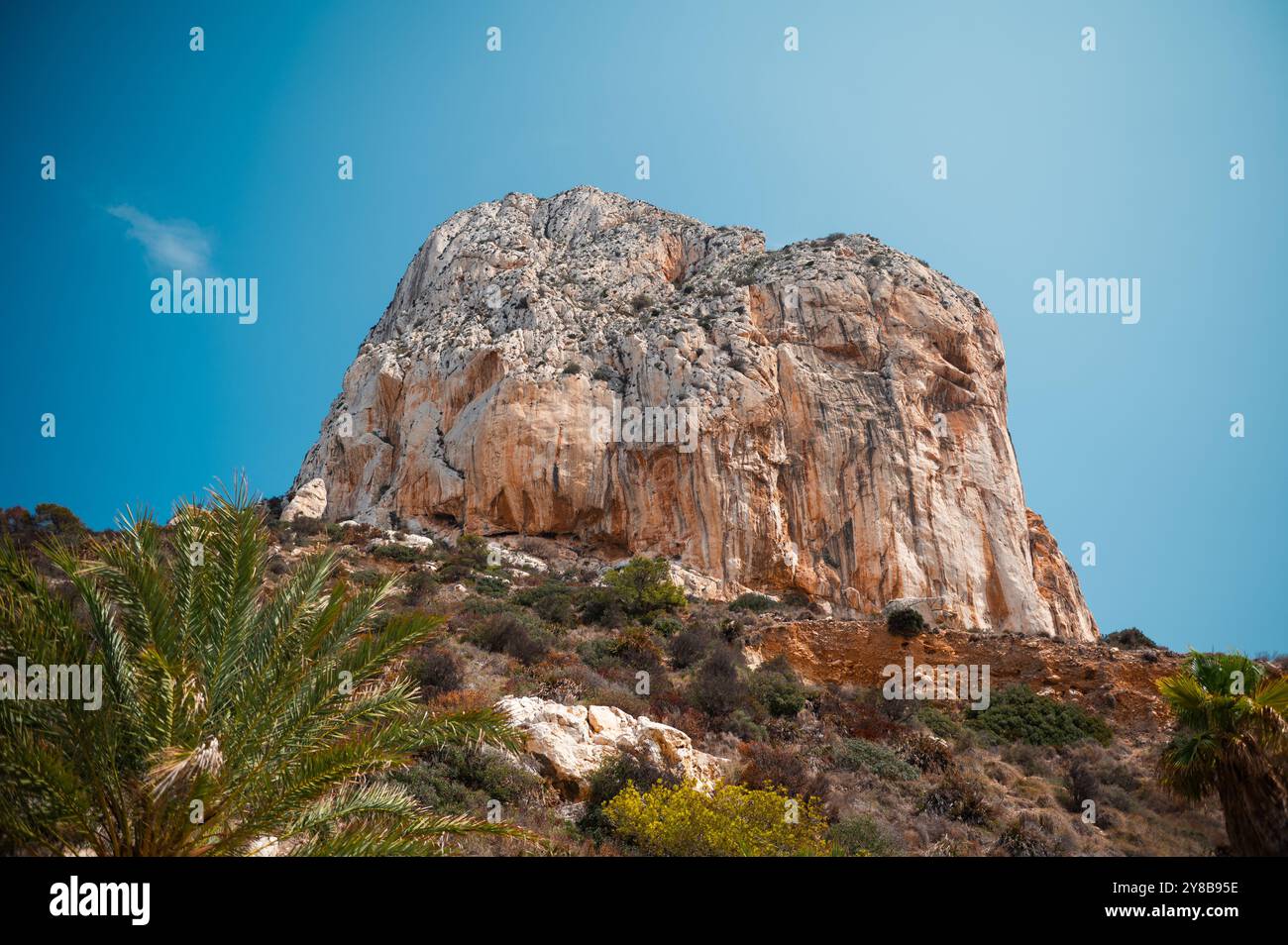 A stunning view of a towering rocky cliff under a clear blue sky ...