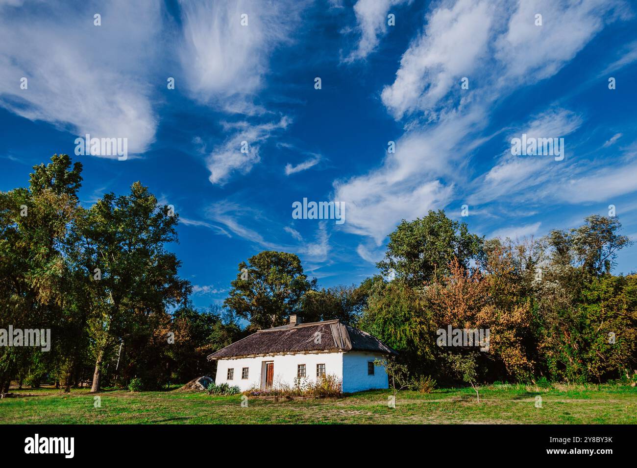 Traditional rural house with a thatched roof is nestled in a peaceful ...