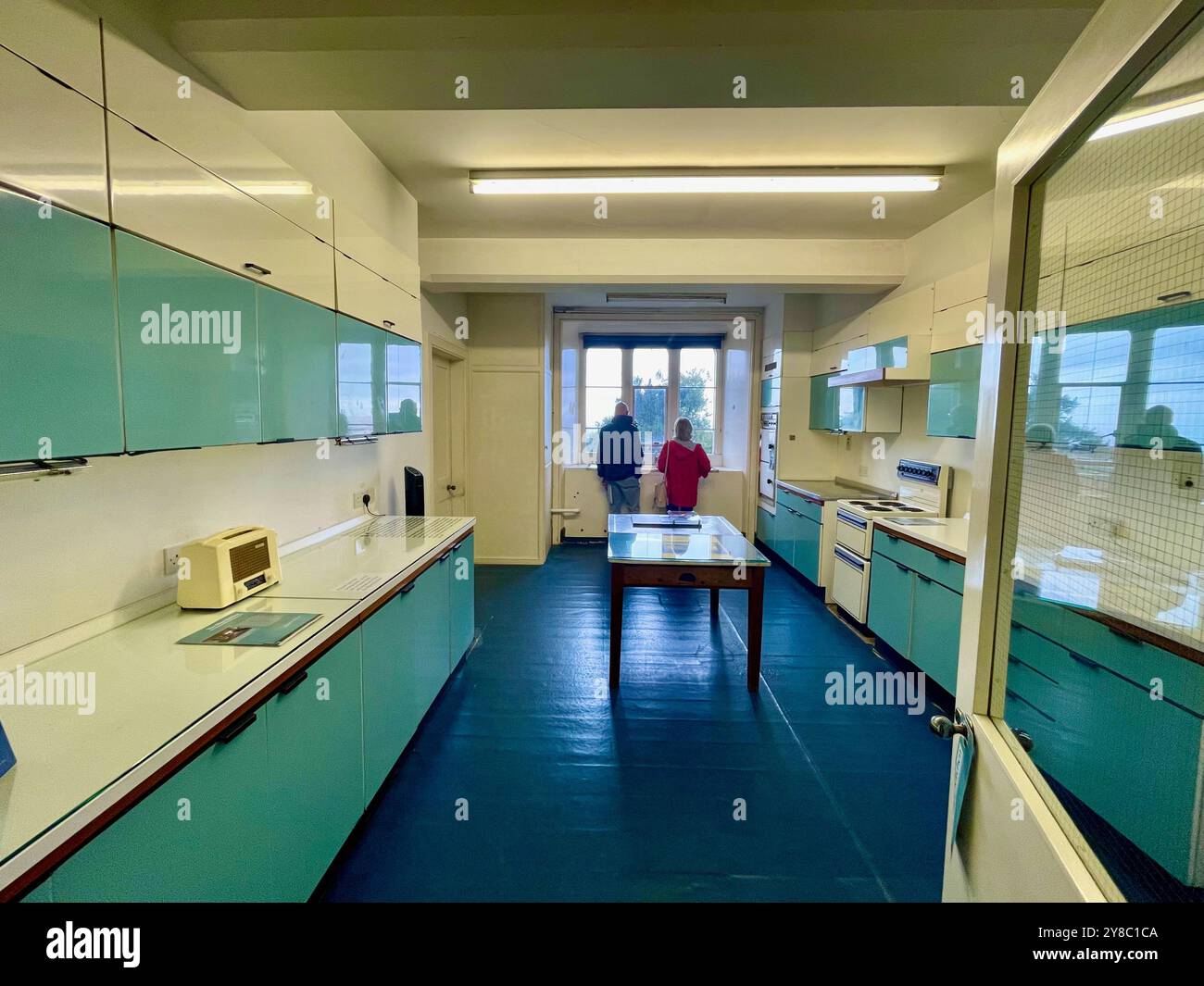 two visitors look out of the window of the blue kitchen at dunster ...