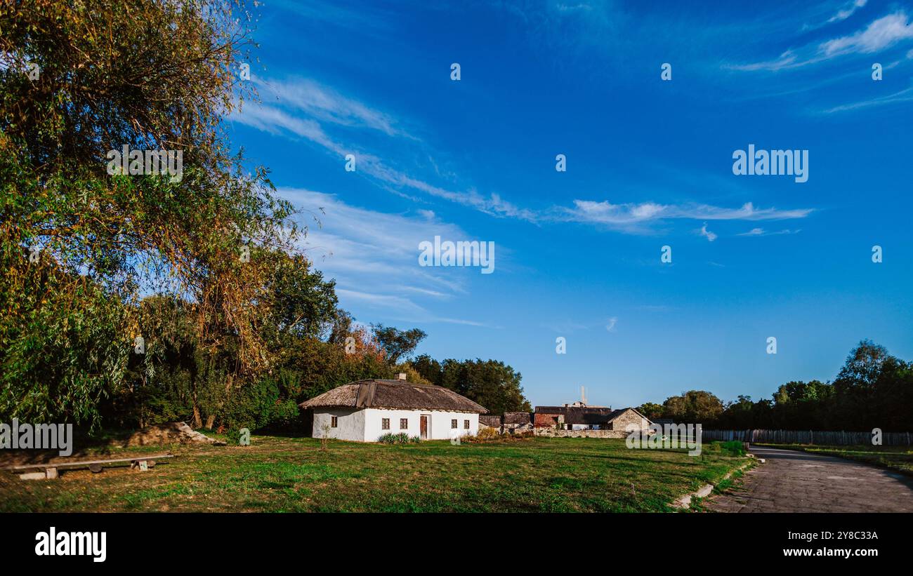 Peaceful rural scene featuring a traditional thatched-roof house and a ...