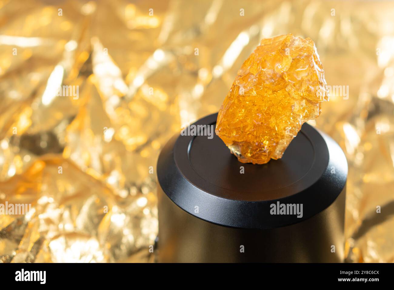 A close-up of a large, translucent amber crystal resting on a black ...