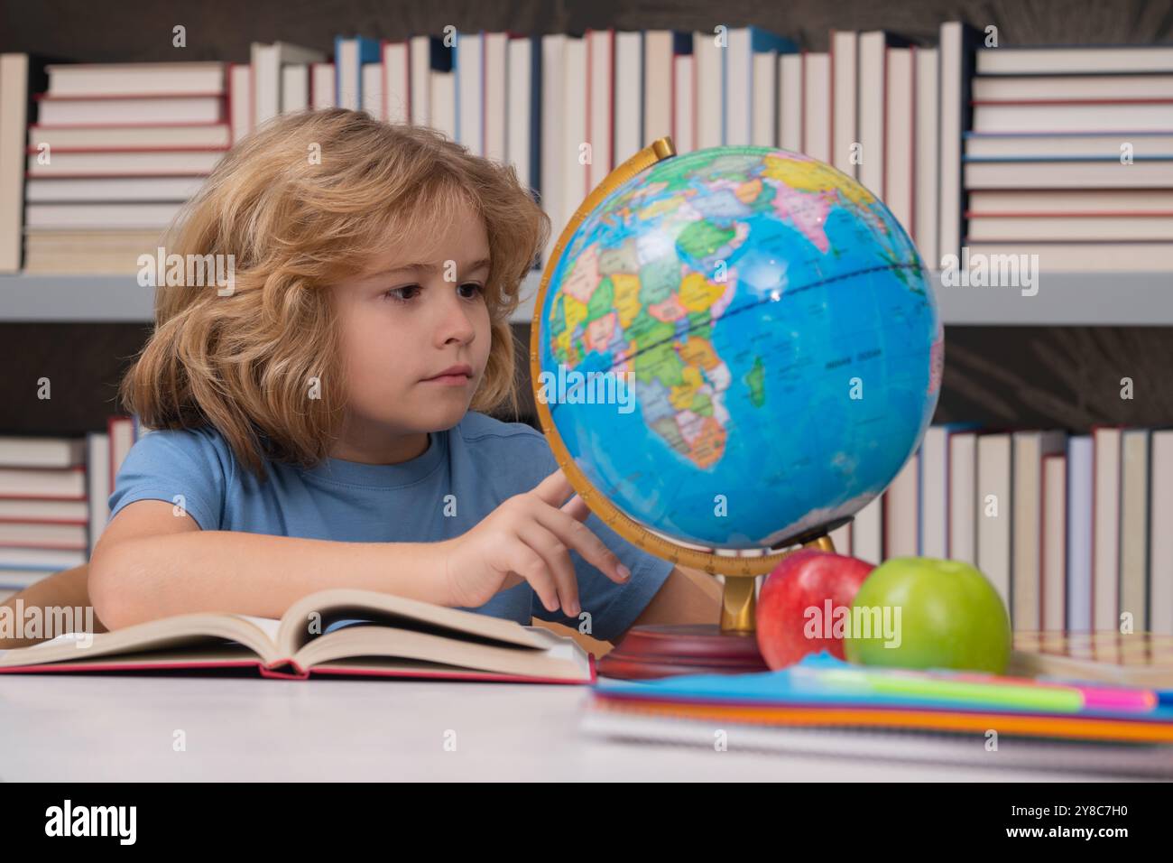 School pupil looking at globe in library, geography lesson. School and ...