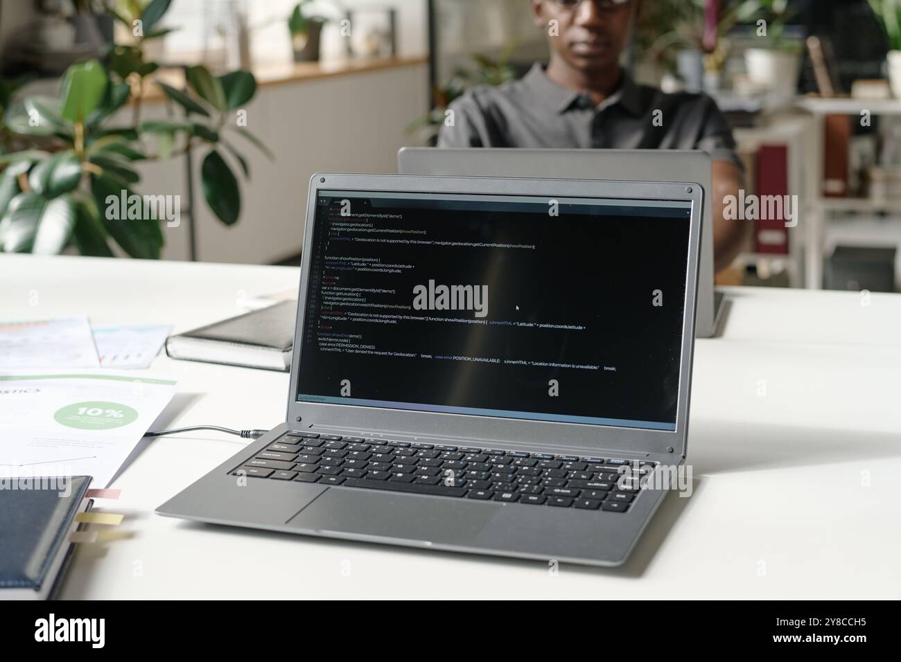 Medium close up of silver laptop with codes on black screen in modern ...