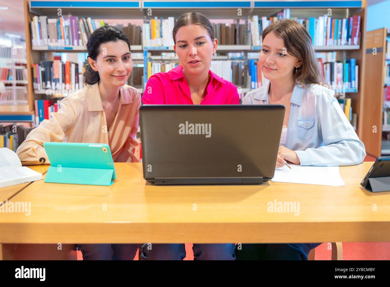 Three Young Women Studying Together in a Library with Laptops and ...