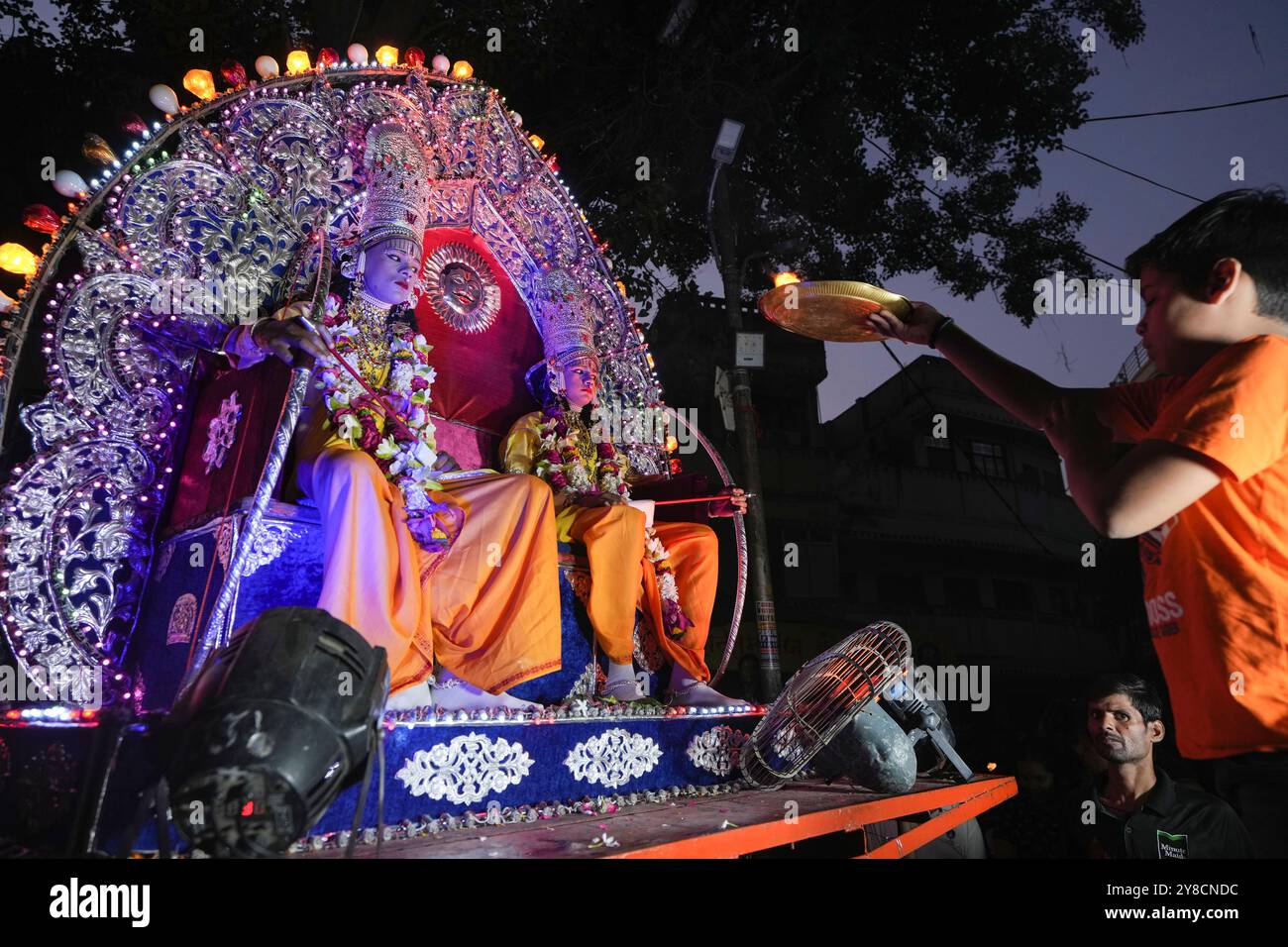 A Hindu devotee holds a traditional oil lamp as he offers prayers to ...