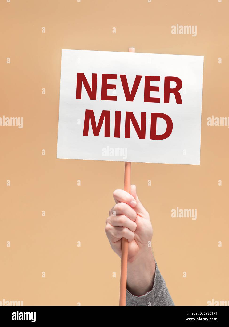 male hand holding a white sign with phrase NEVER MIND in bold red ...