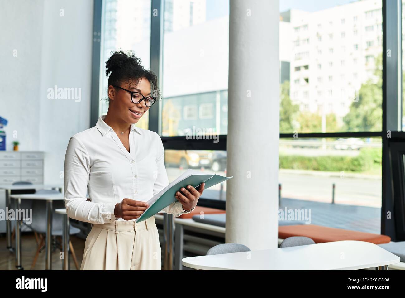 The teacher smiles warmly while reviewing her lesson plan in a bright ...