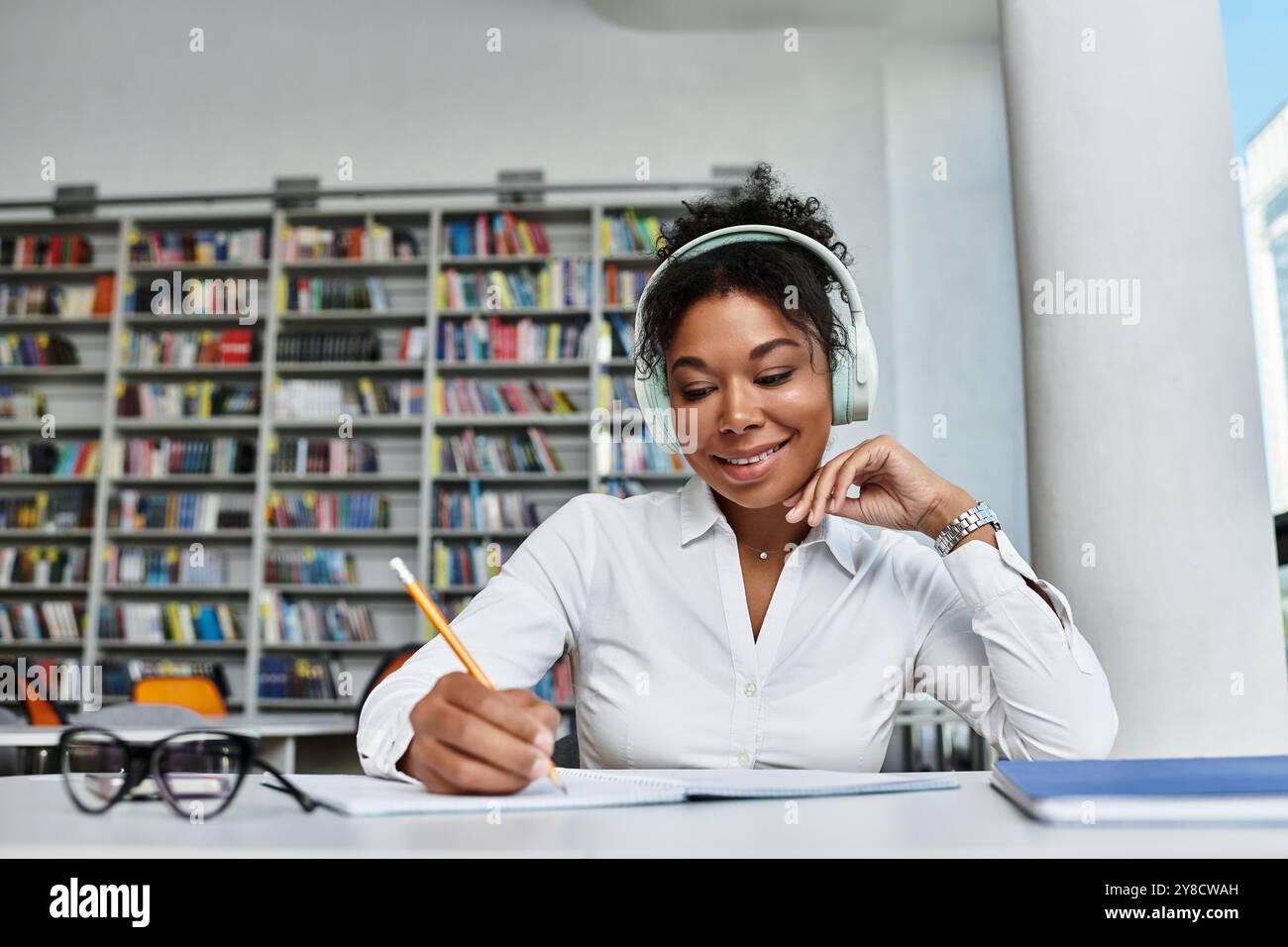 An inspiring teacher with headphones works diligently at her desk ...