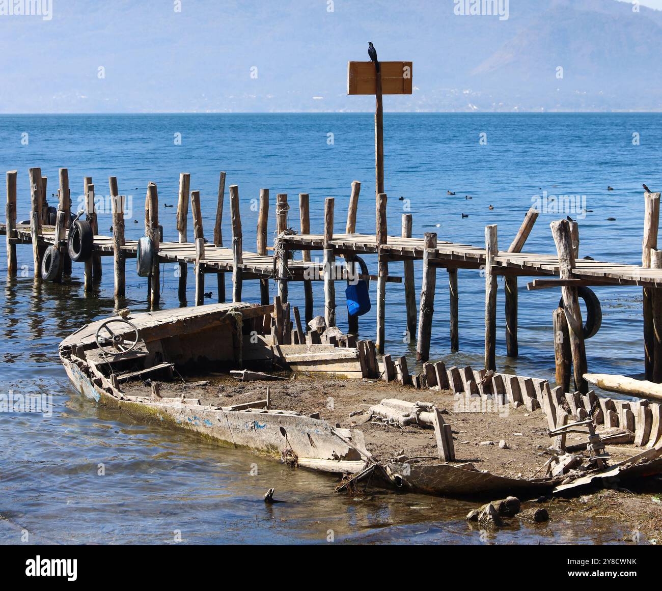 Derelict half submerged craft on Lake Atitlan. Rustic, old jetty at the ...