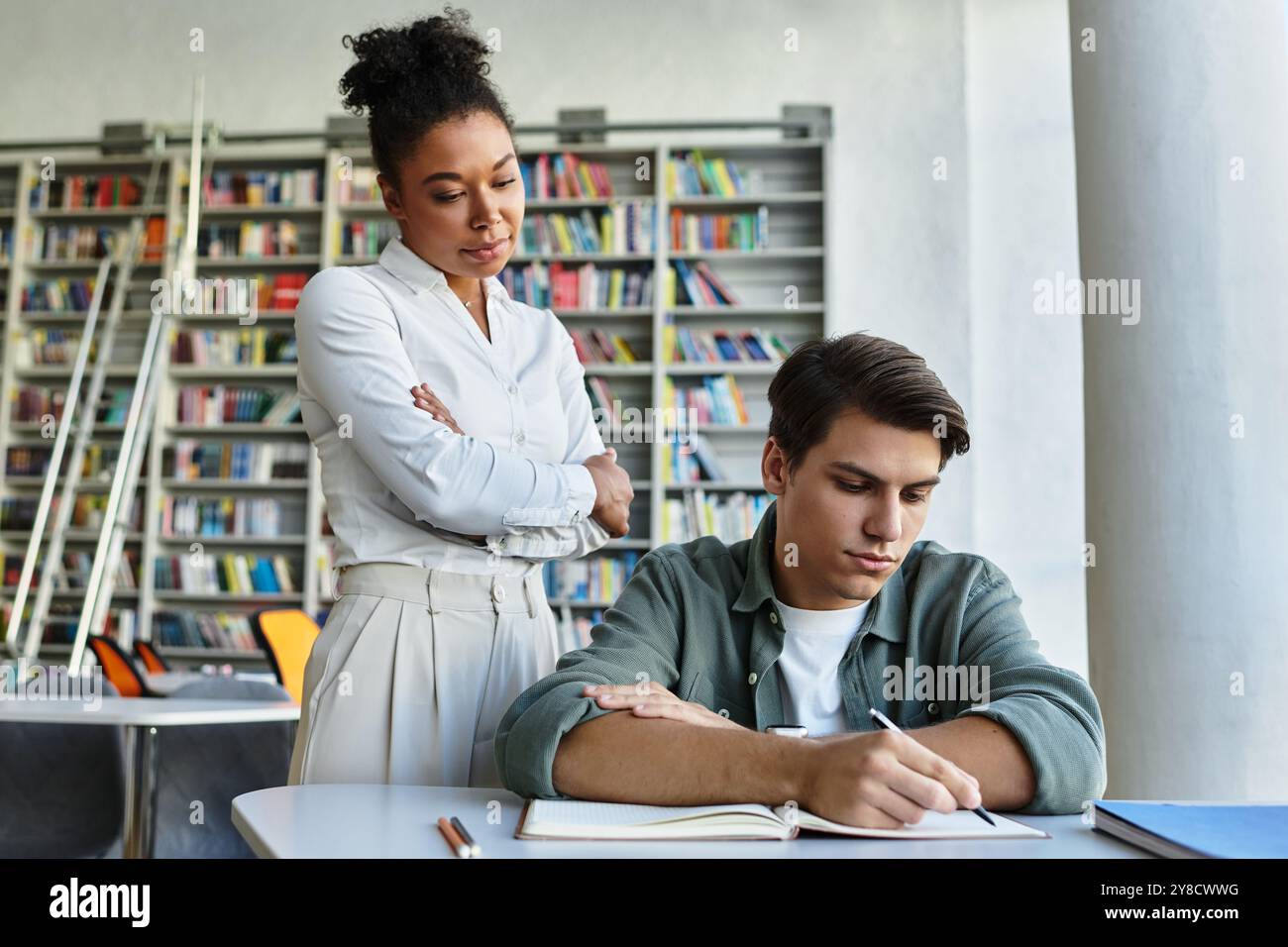 A mentor guides a student as he focuses intently on his notes in the ...