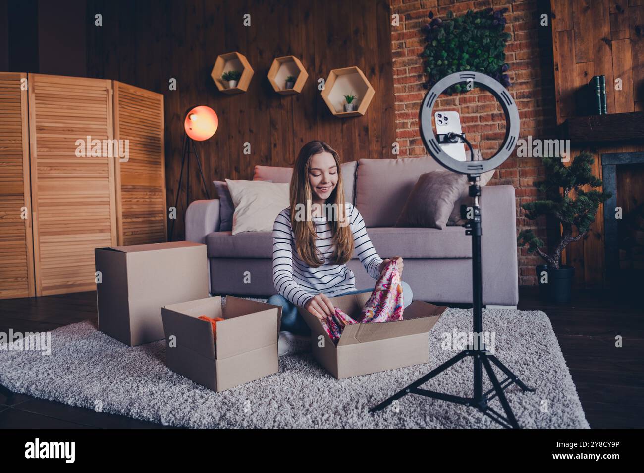 Full size photo of cute young girl unpack clothes tripod holder smart ...