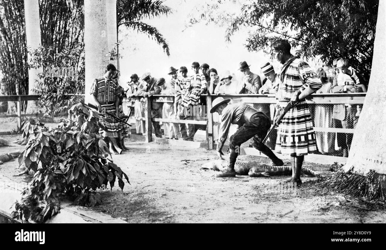 Two Mikasuki Seminole men hold rifles while a white man wrestles an ...