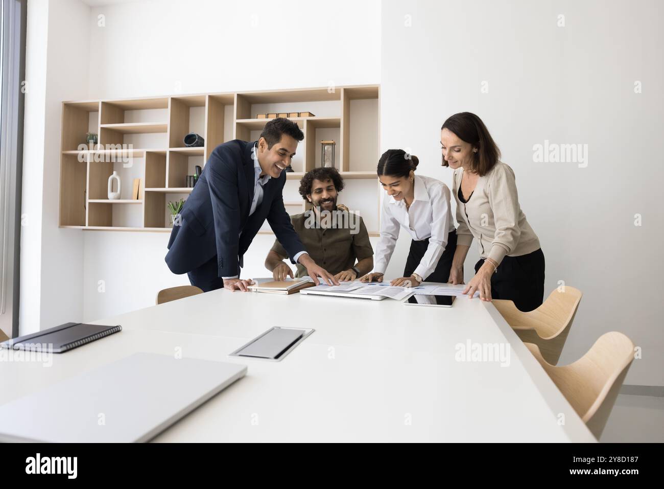 Four multicultural colleagues gather together for paperwork around ...