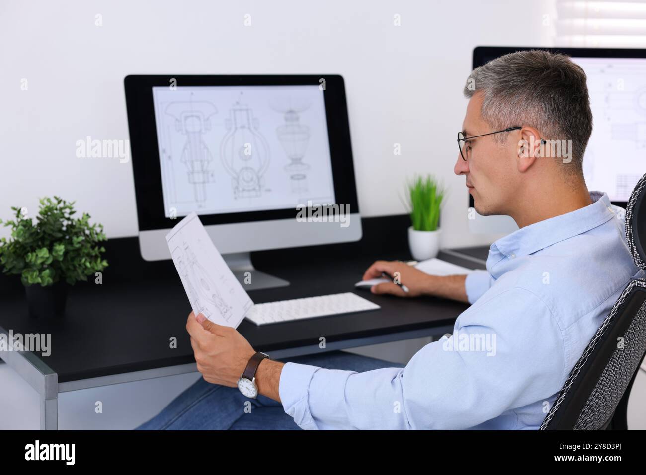 Architect checking engineering drawing at table in office Stock Photo ...