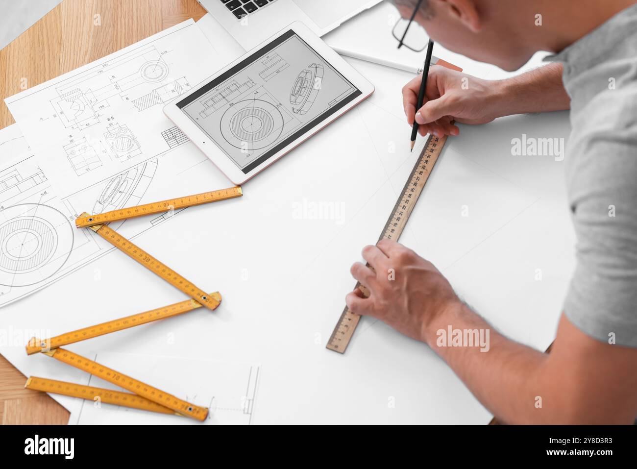 Architect making engineering drawing at wooden table in office, above ...