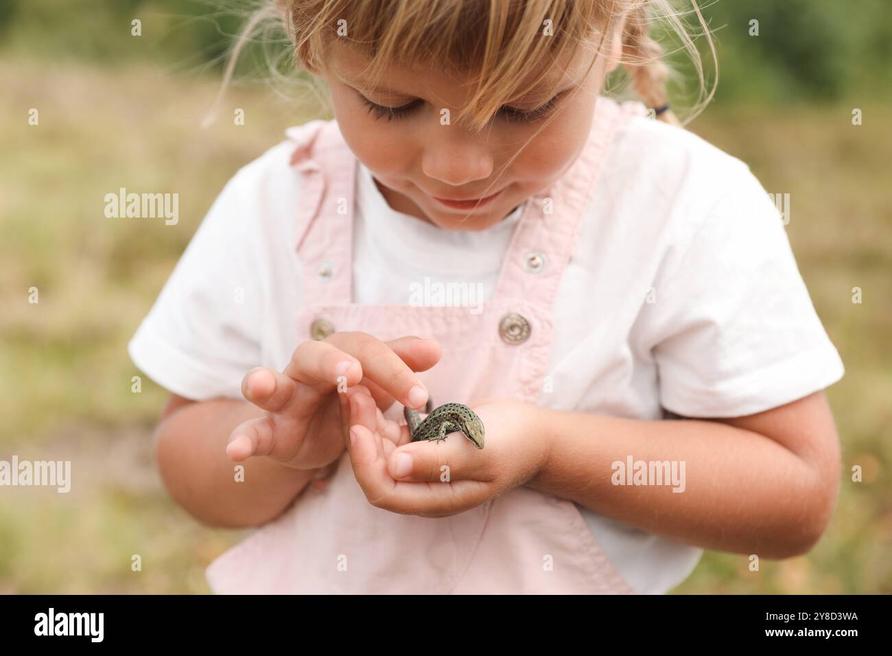 Little girl holding lizard on blurred background. Child enjoying ...