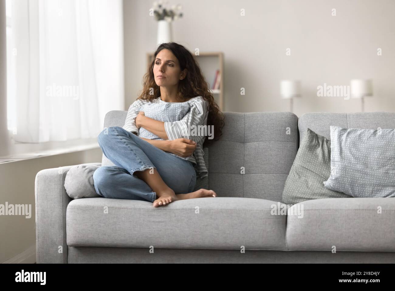 Sad lonely young woman sitting on couch in home interior Stock Photo ...
