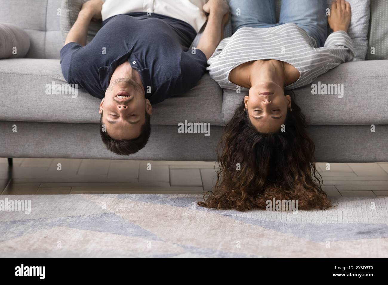 Sleeping young married couple lying upside down on home sofa Stock Photo - Alamy