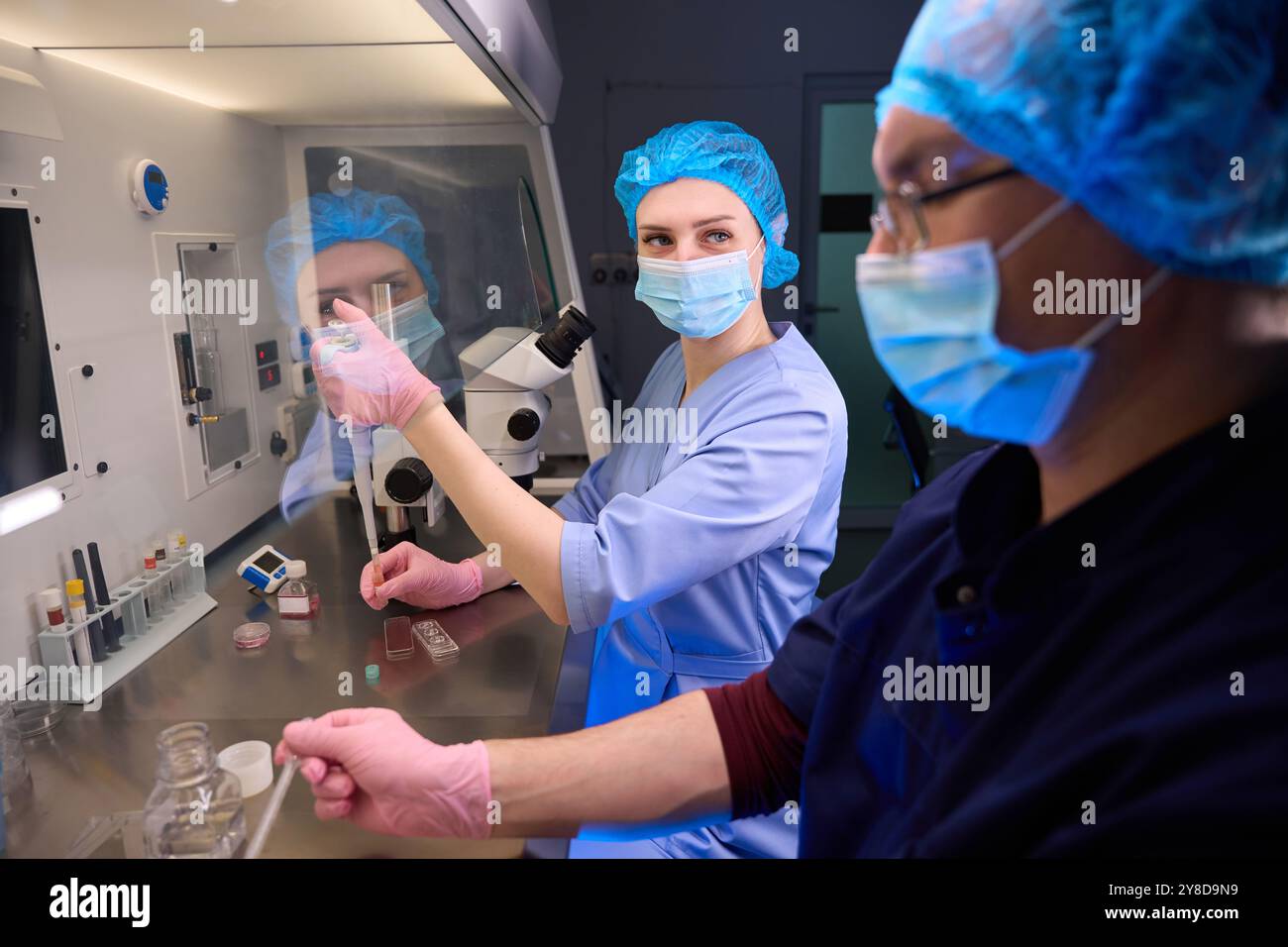 Two embryologists working together in a controlled lab environment ...