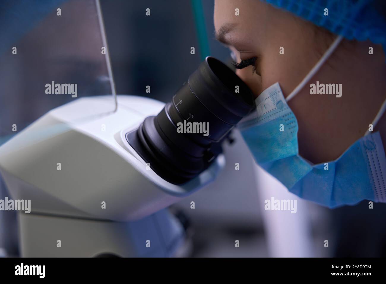 Female embryologist closely observing through a microscope Stock Photo ...