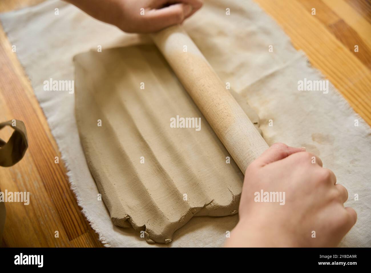 Master rolls out a layer of clay with a wooden rolling pin Stock Photo ...