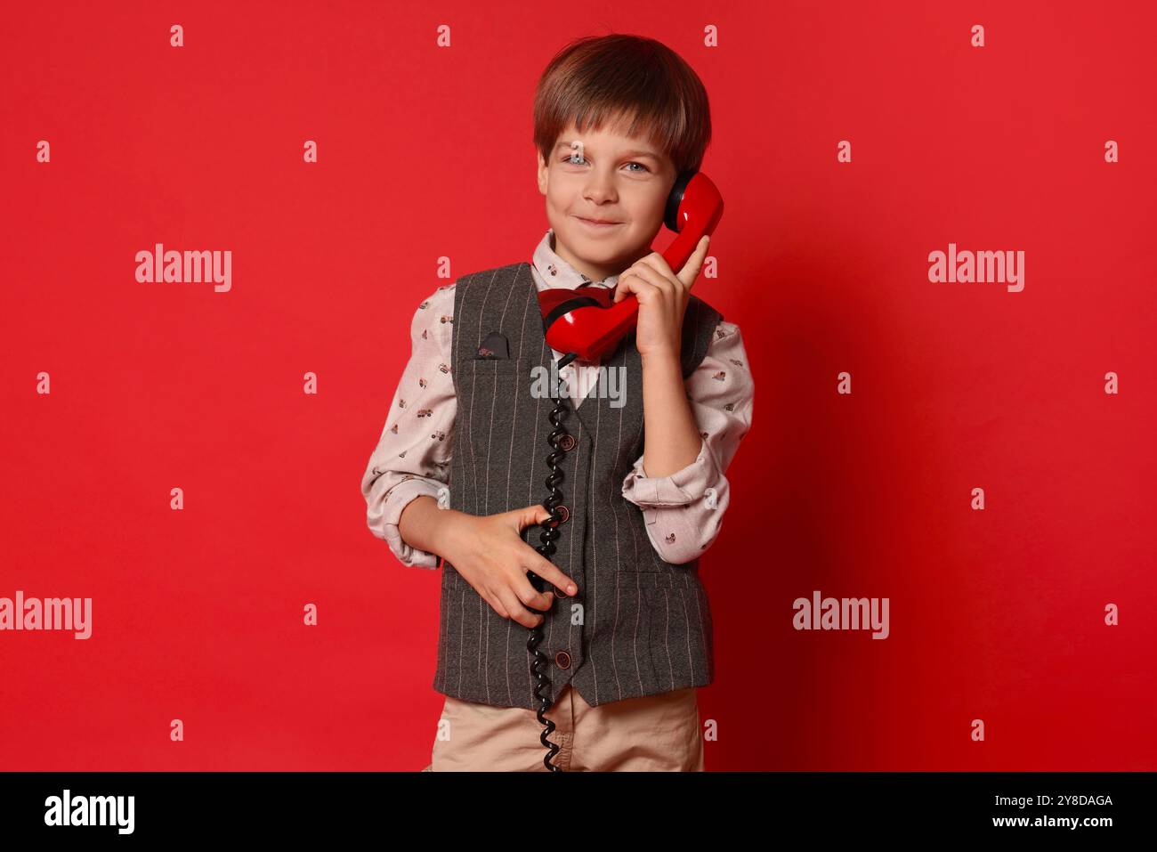 Cute little boy with handset of telephone on red background Stock Photo ...