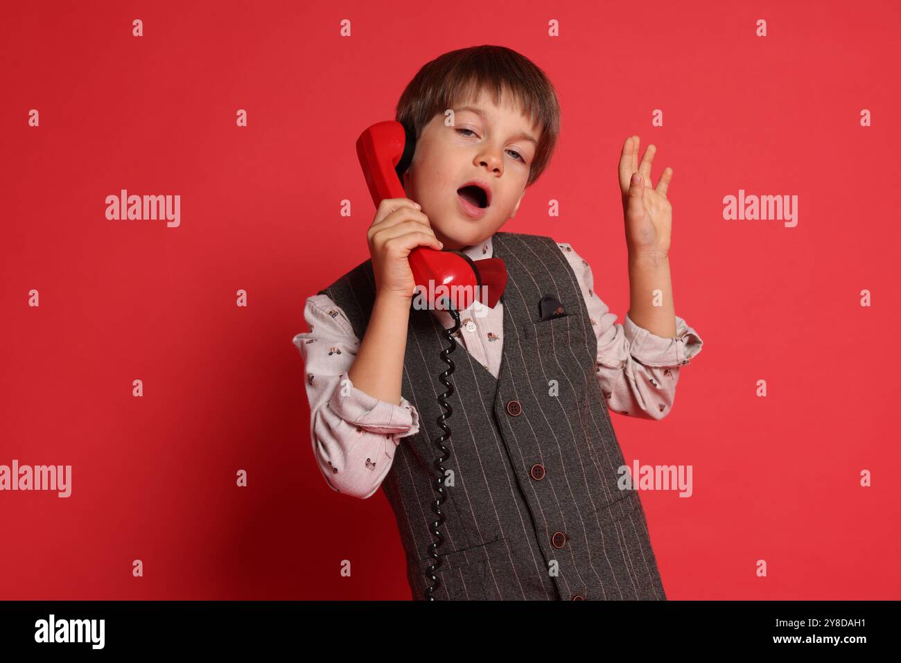 Cute little boy with handset of telephone on red background Stock Photo ...