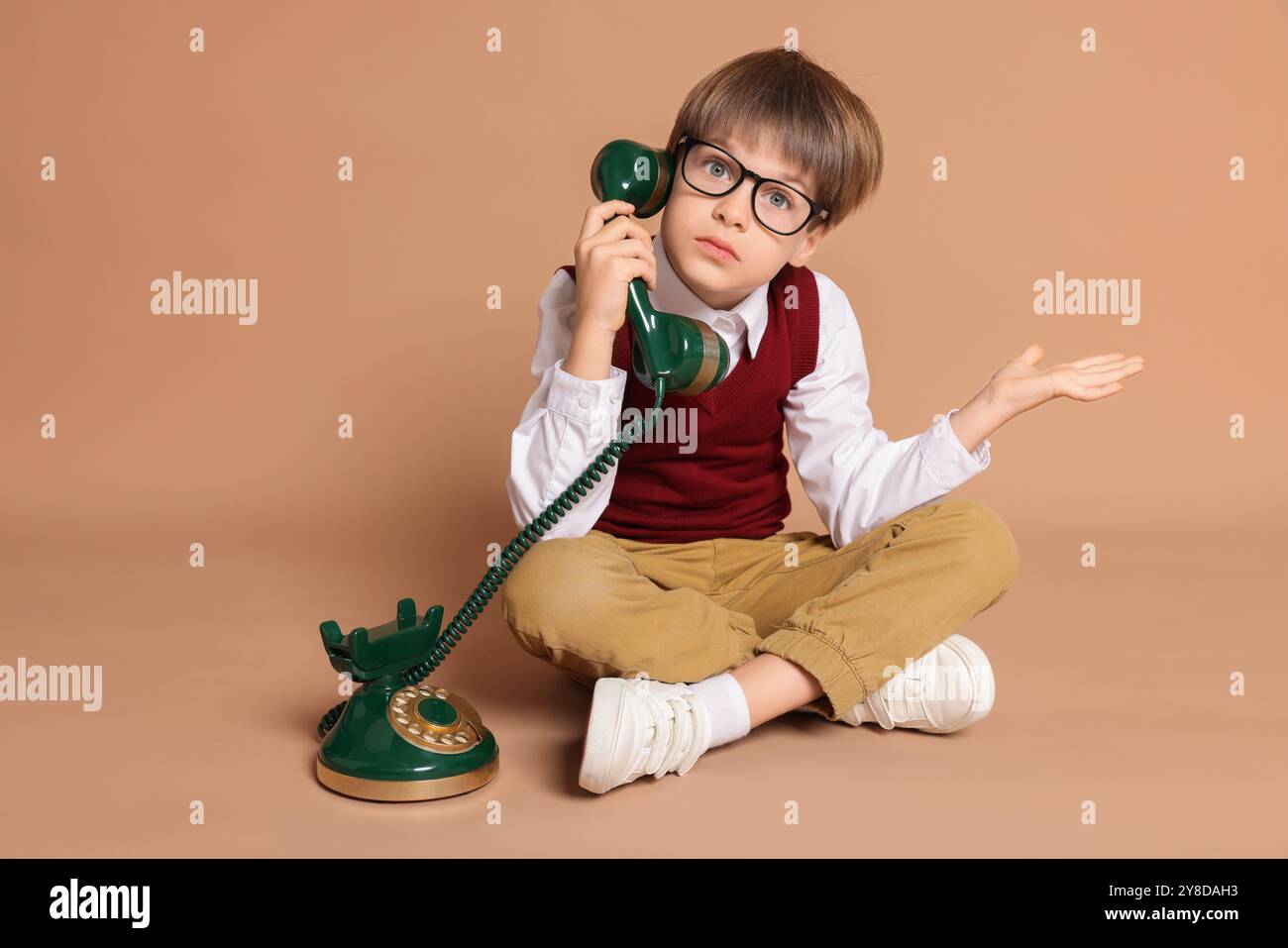 Cute little boy with old telephone on beige background Stock Photo - Alamy