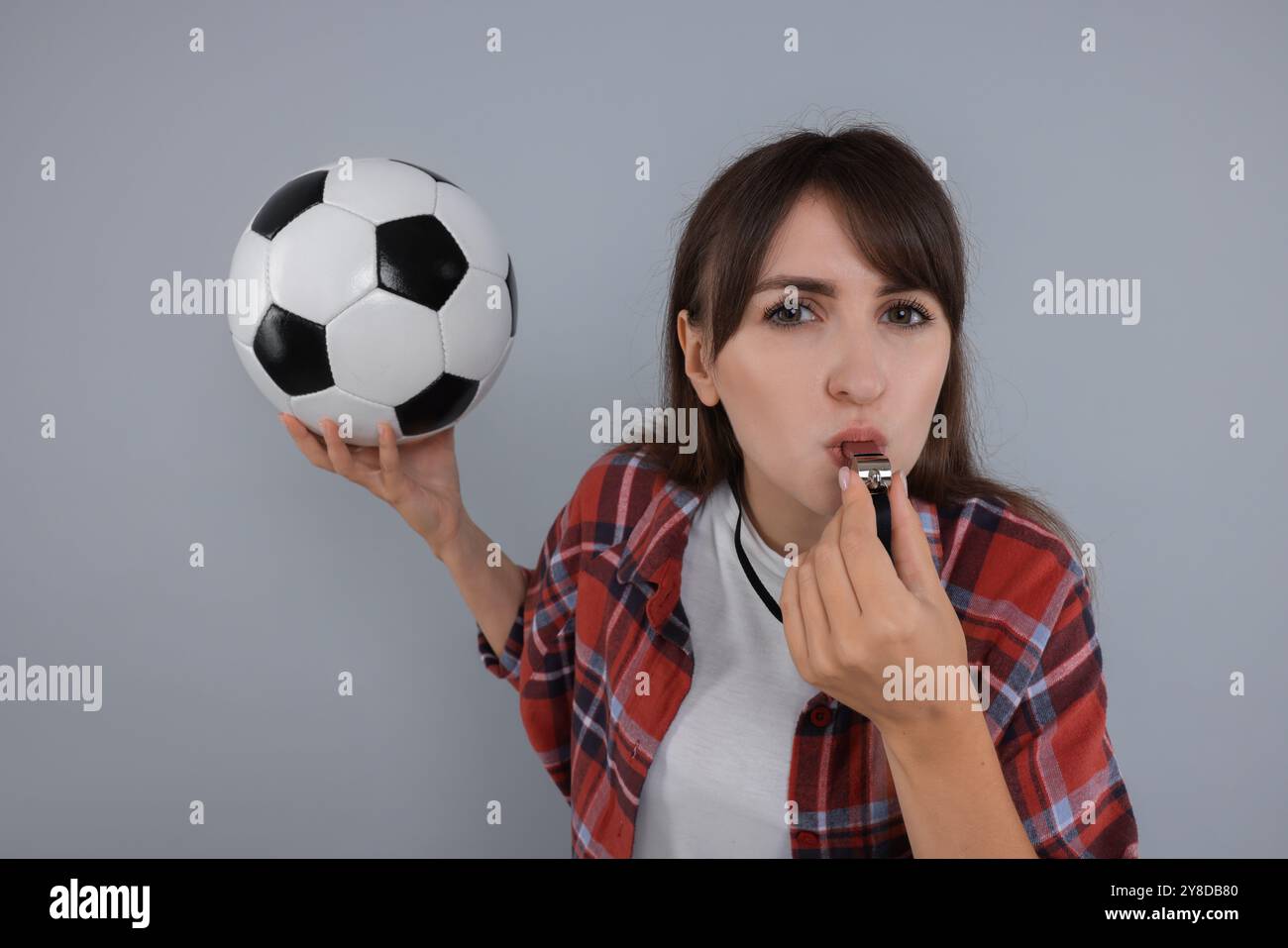 Woman with soccer ball blowing whistle on grey background Stock Photo ...