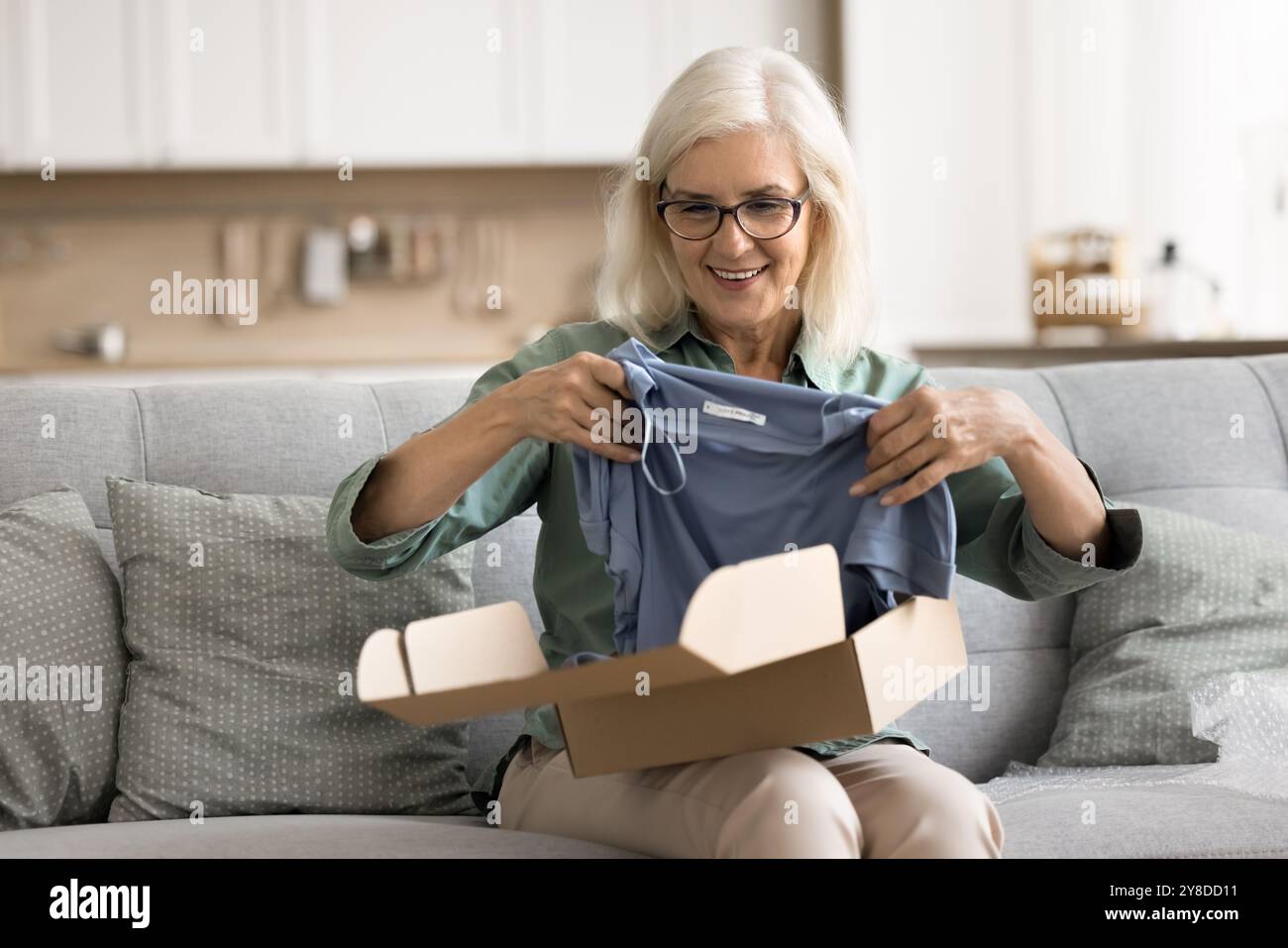 Happy older woman opening parcel box with bought fashion apparel Stock ...